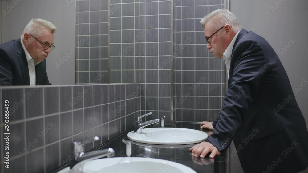 Senior business man in office bathroom in despair. Frustrated ...