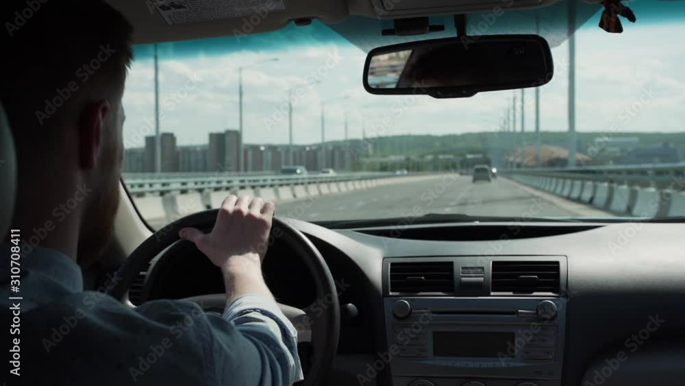 man driving car in a city in a summer day. shot of the road from inside ...