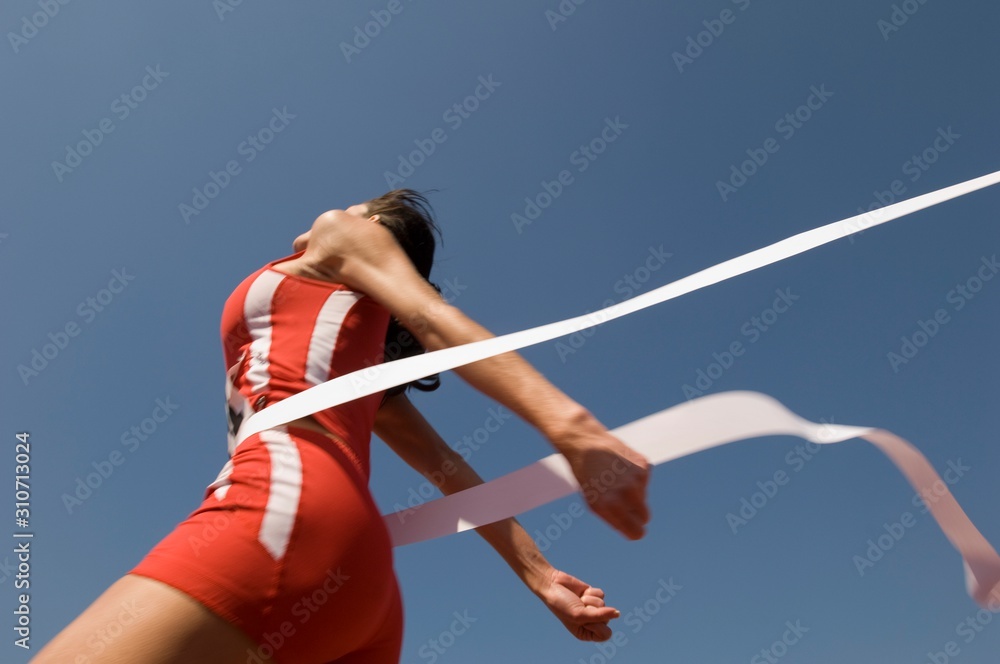 Female Athlete Crossing Finish Line Against Blue Sky Stock Photo ...