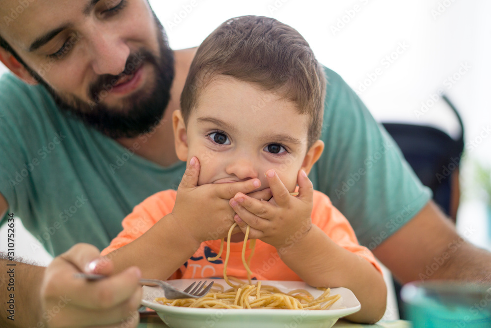 Boy eating spaghetti with his father Stock Photo | Adobe Stock