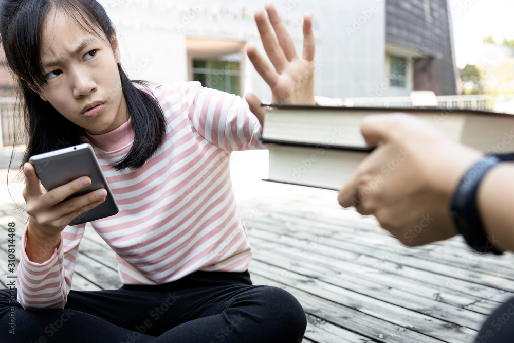 Asian child girl is avoiding reading book,she wants to use a mobile ...