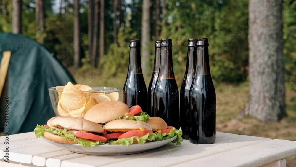 Outdoors party in forest. Dinner at the camping. Bottled beer and ...