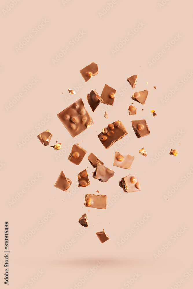 Flying in the air broken bar of milk chocolate with nuts and flakes on ...