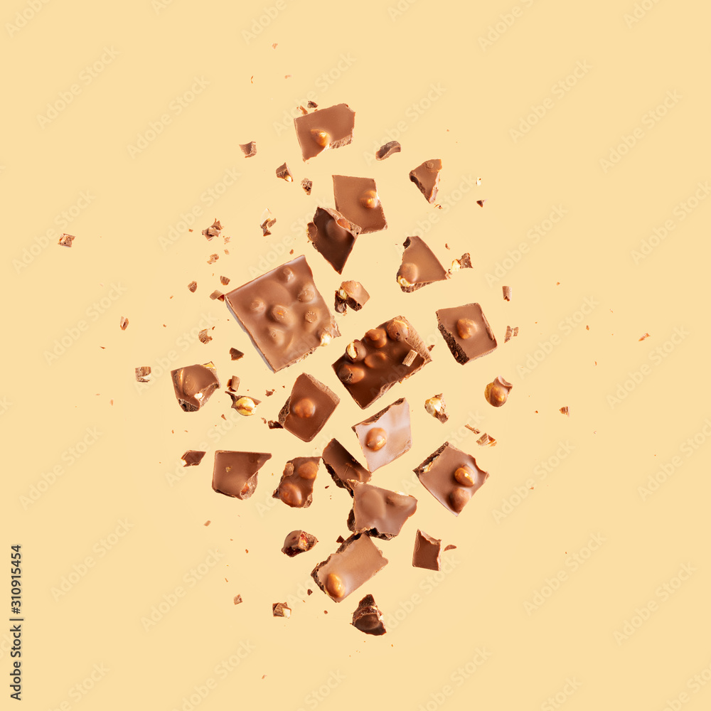 Flying in the air broken bar of milk chocolate with nuts and flakes on ...