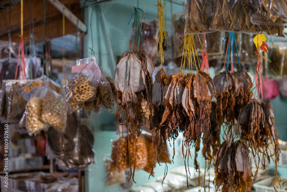 Dried fish tied into several bundles for sale, hanging from above, in a ...