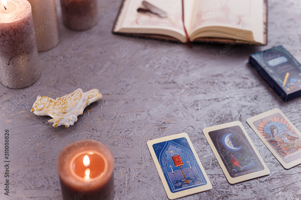 Divination cards alignment with feathers and candles on silver ...