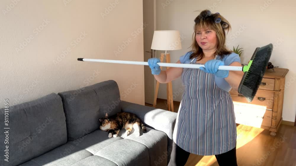 fat middle aged woman, housewife in apron performs physical exercises ...
