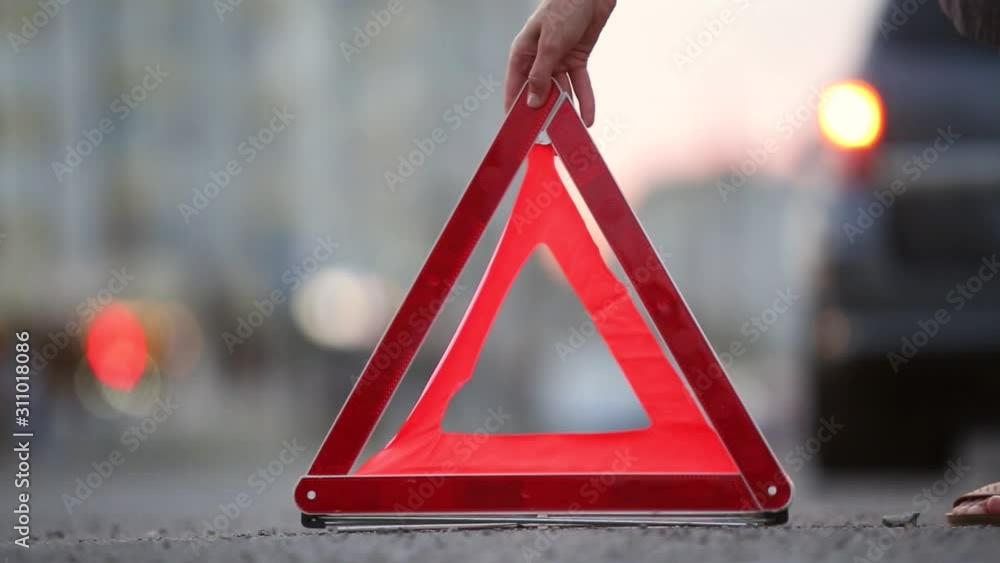 Woman driver putting an emergency stop sign behind broken blurred car ...