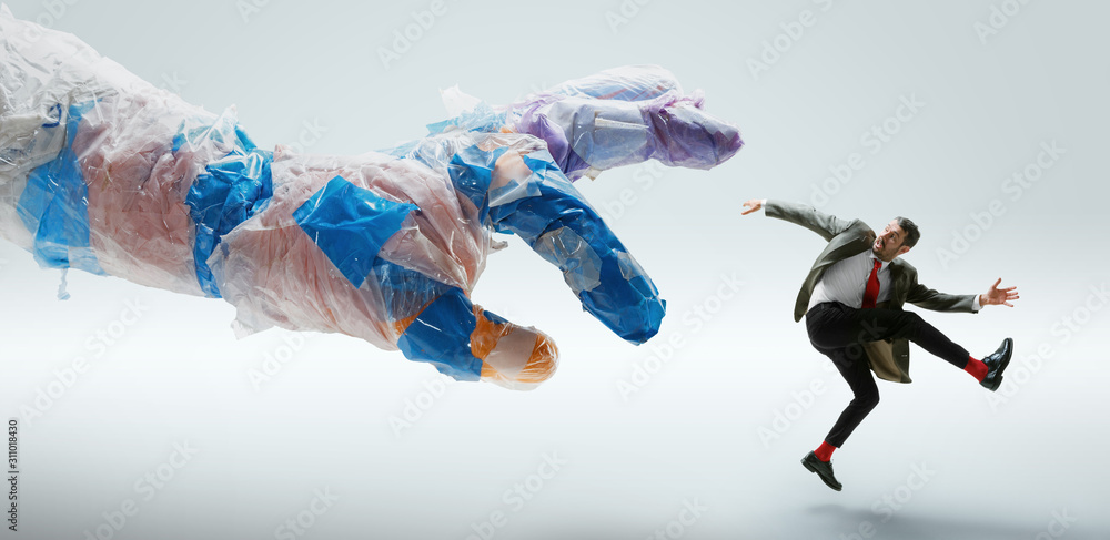 Foto Stock Young caucasian man avoiding big plastic hand on white ...