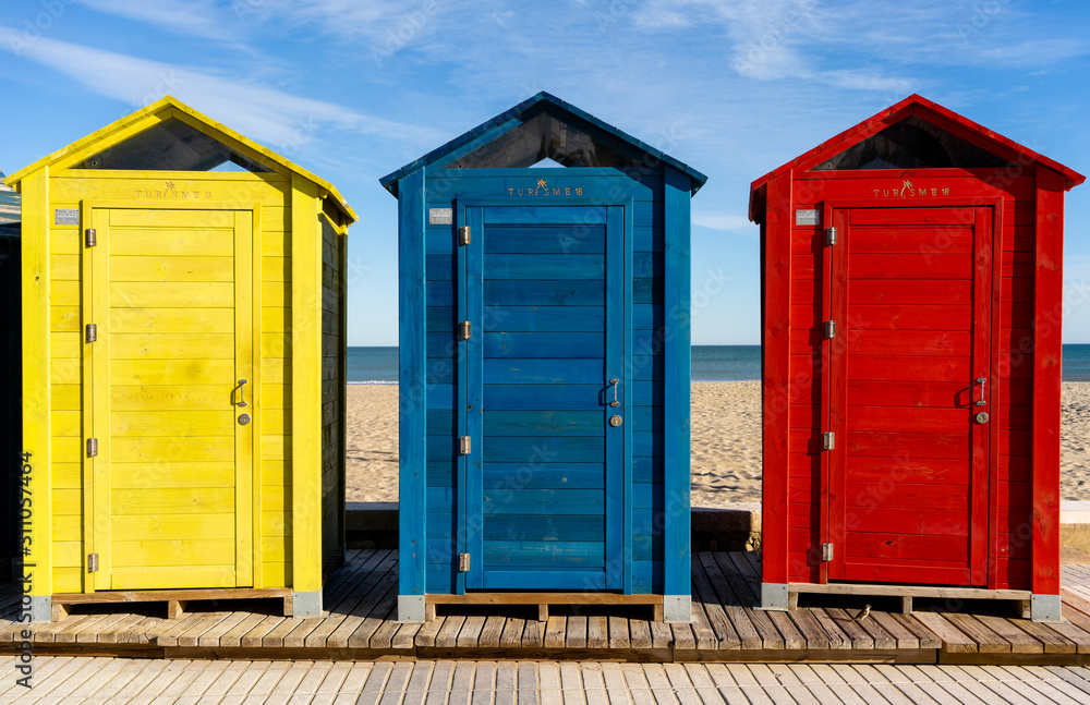 row of beach yellow blue and red huts and cabins with see and beach in ...