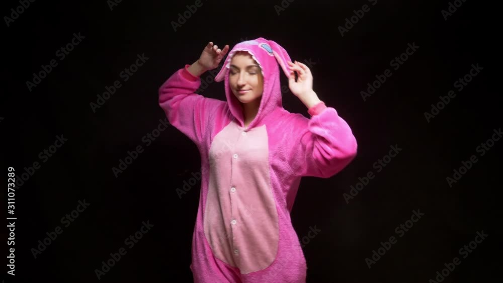 girl in pink pajamas kigurumi in VR glasses on a black background ...