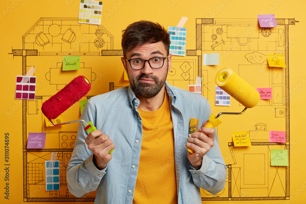 Doubtful Bearded Painter Man Paints Walls With Roller Chooses Between doubtful-bearded-painter-man-paints-walls-with-roller-chooses-between