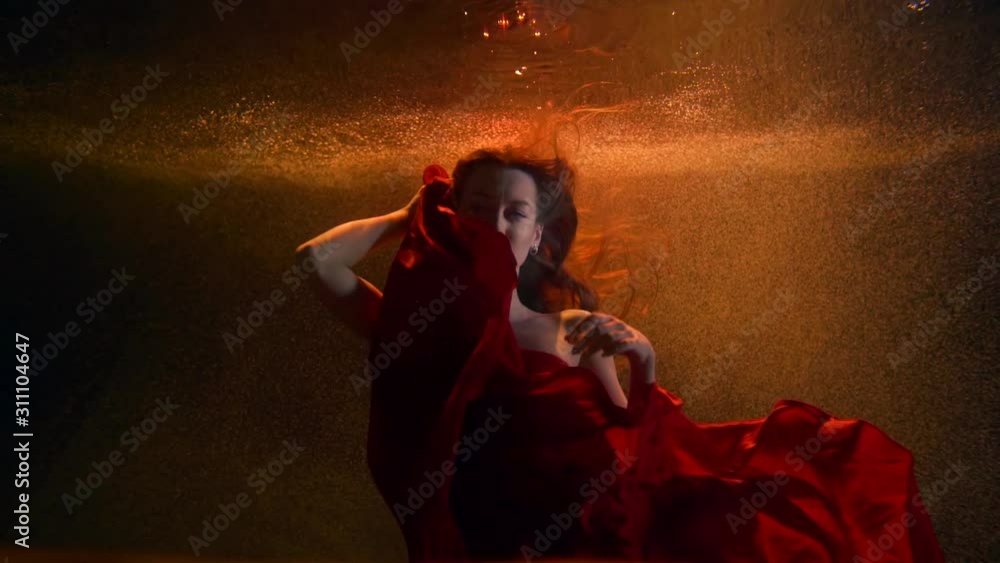 Portrait of a girl in a flowing red suit, she is underwater on an ...