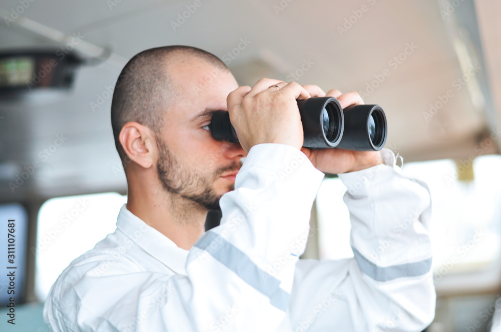Sailor navigator, the third assistant to the captain looks through ...