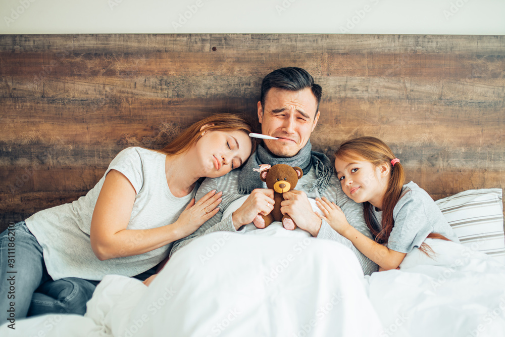 sick caucasian man lying on bed with high temperature with careful wife ...