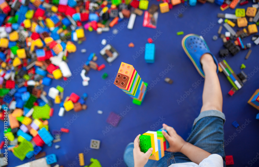 4 years boy building a tower with with interlocking plastic bricks game ...