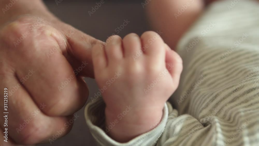 Stockvideo Newborn baby squeezing grandpa's hand. A closer look of a ...