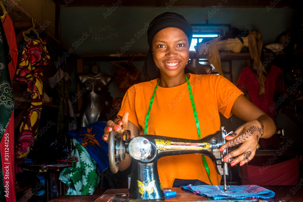 portrait of a young african female tailor smiling while working with ...