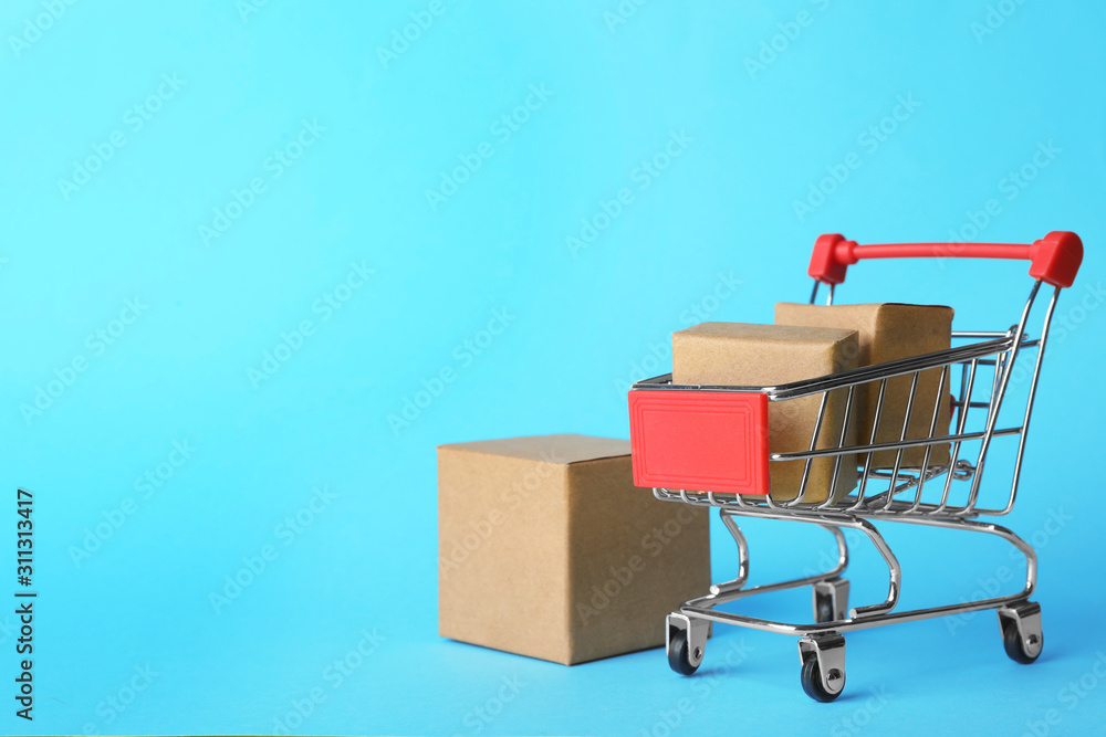 Shopping cart and boxes on light blue background, space for text ...