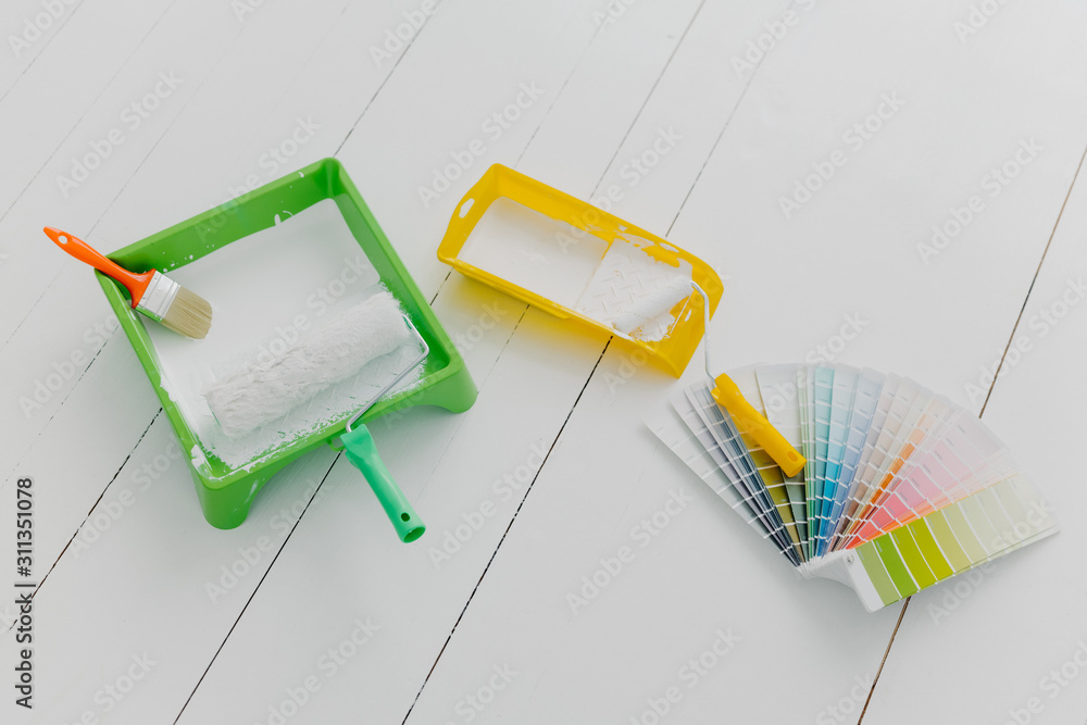 Top view of paint trays, brushes and rollers, color palette sample ...