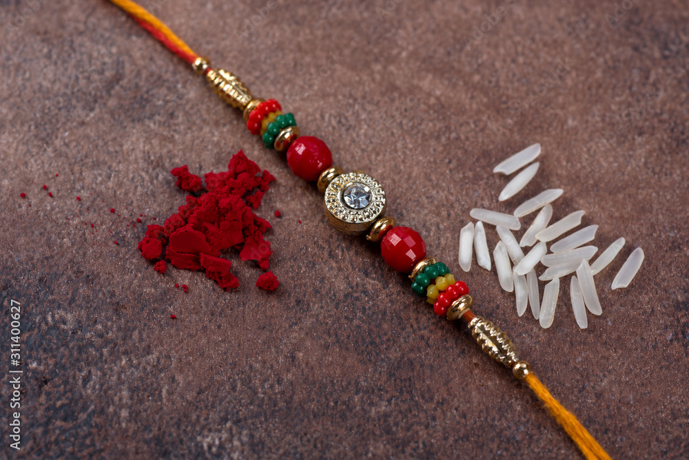 Raksha Bandhan : Rakhi with rice grains and kumkum on stone background ...
