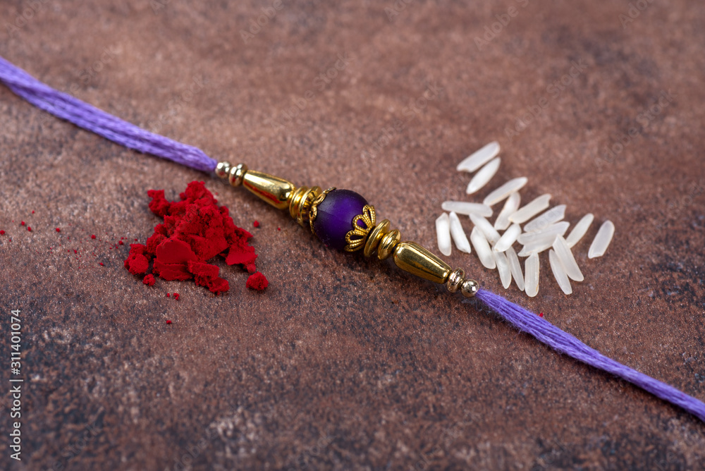 Raksha Bandhan : Rakhi with rice grains and kumkum on stone background ...