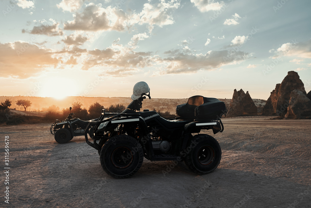 Quad ATV parked on sand without drivers on sunset background in ...