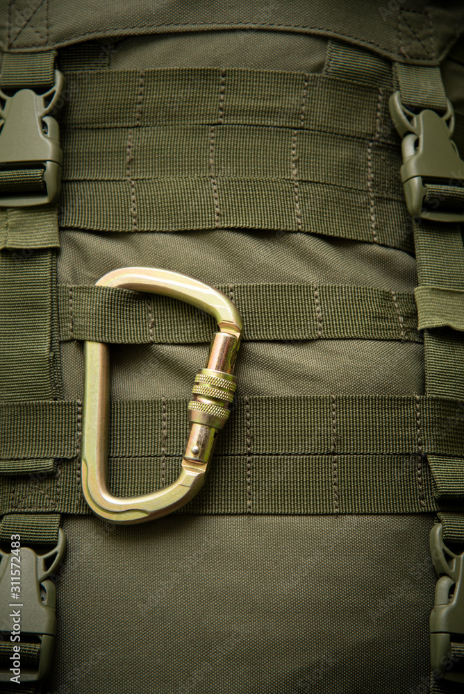 steel climbing carabiner attached to a green military tactical backpack ...