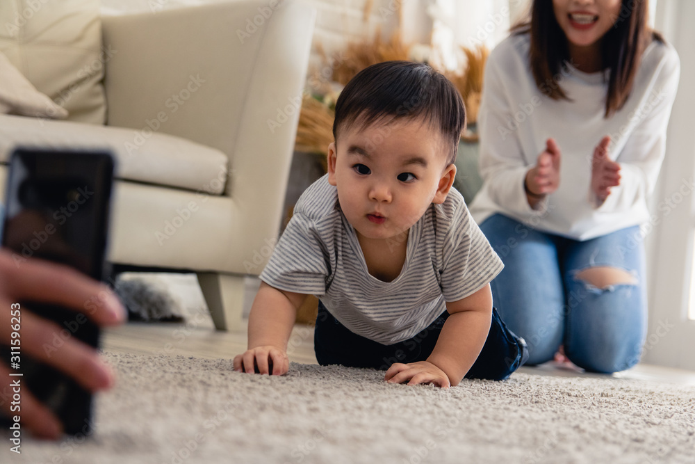 The asian baby crawled towards the smartphone With curiosity, ignoring ...