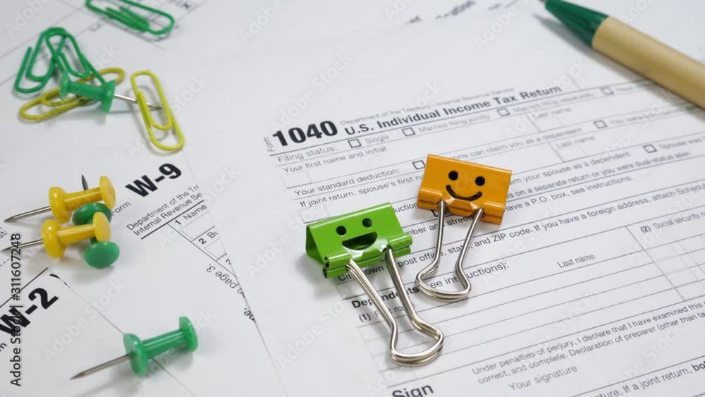 W-9 and 1040 Taxe Form paper blanks lies on table. Green orange color ...