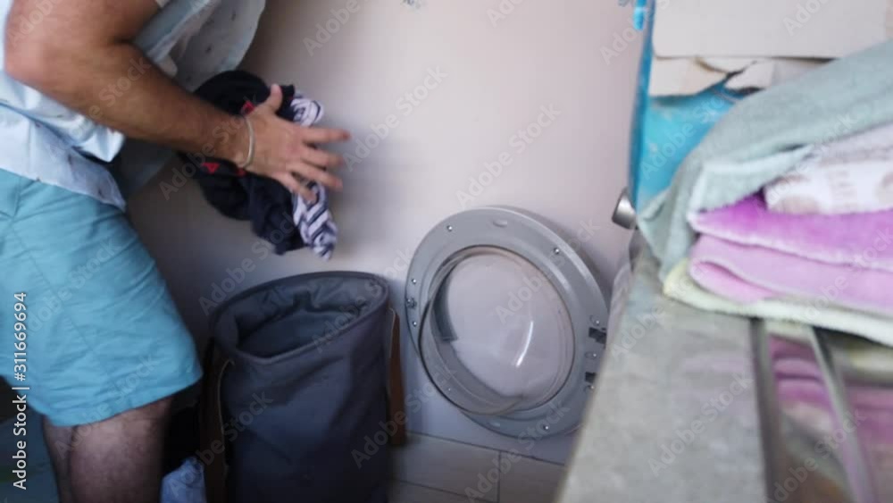 man in the laundry putting a load of washing into a front load washing ...