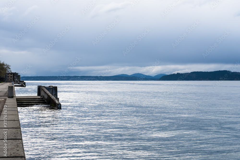 Steps going to the beach at high tide dark clouds and mountains over ...