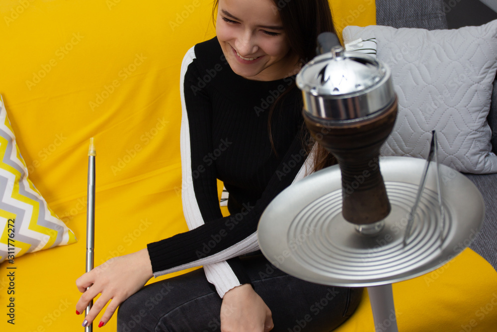 Recreation and entertainment. Young beautiful girl smokes a hookah in a ...