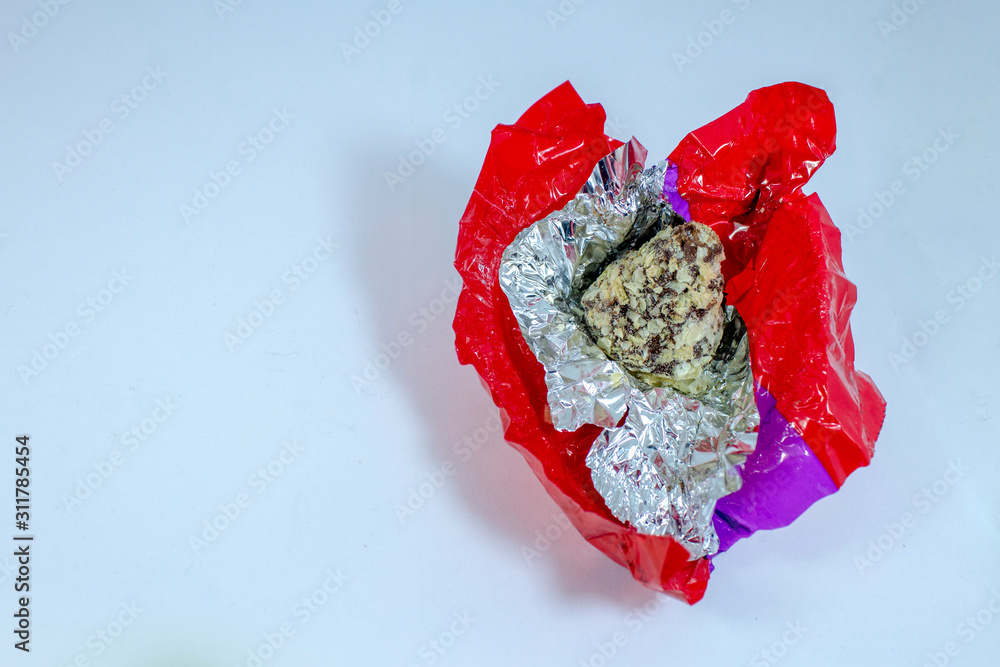 Chocolate wafer candy in foil and red candy wrapper on a white ...