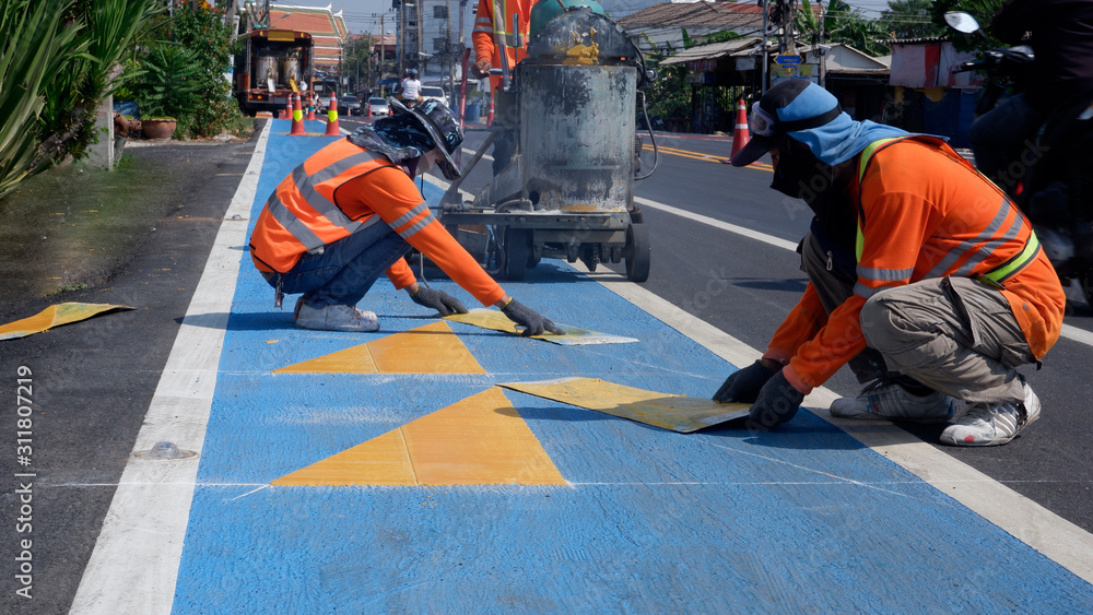 Road workers group in reflective vests with thermoplastic spray road ...