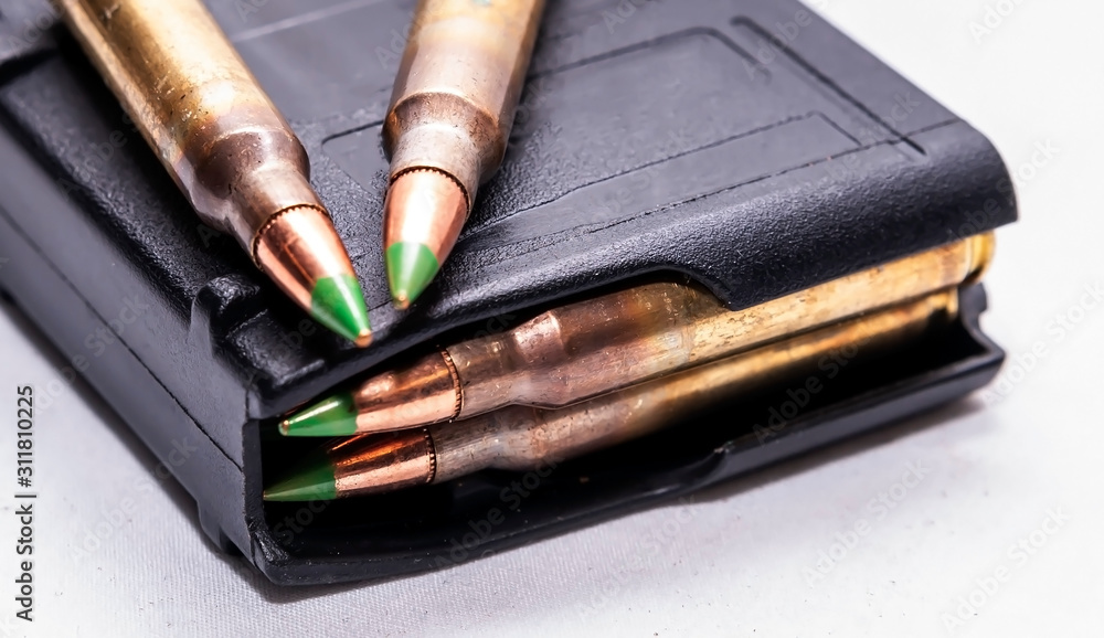 Two .223 caliber green tip bullets laying on a loaded rifle magazine on ...