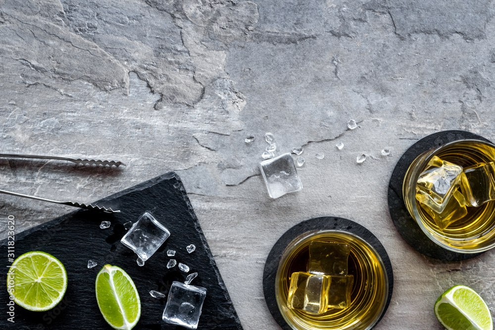 Bar background with whiskey and ice on grey stone desk top-down frame ...