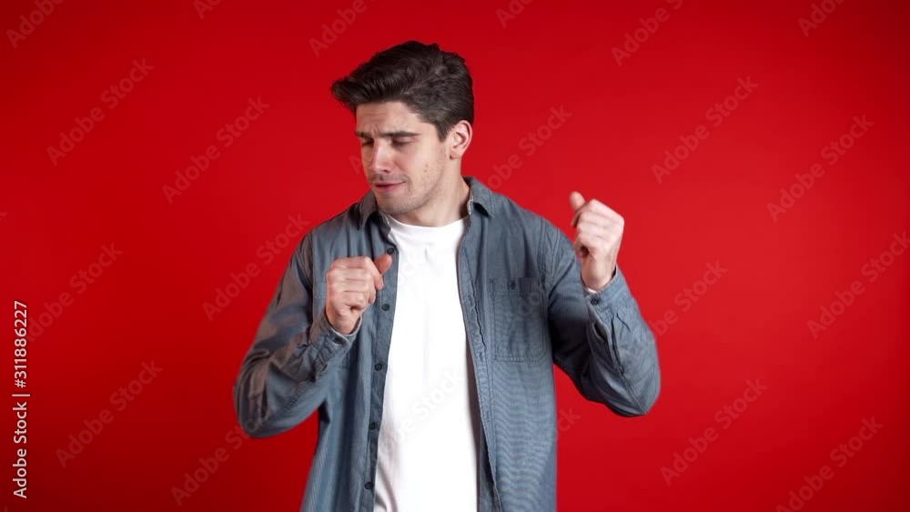 Hipster man moving to the music on red studio background. Dancing ...