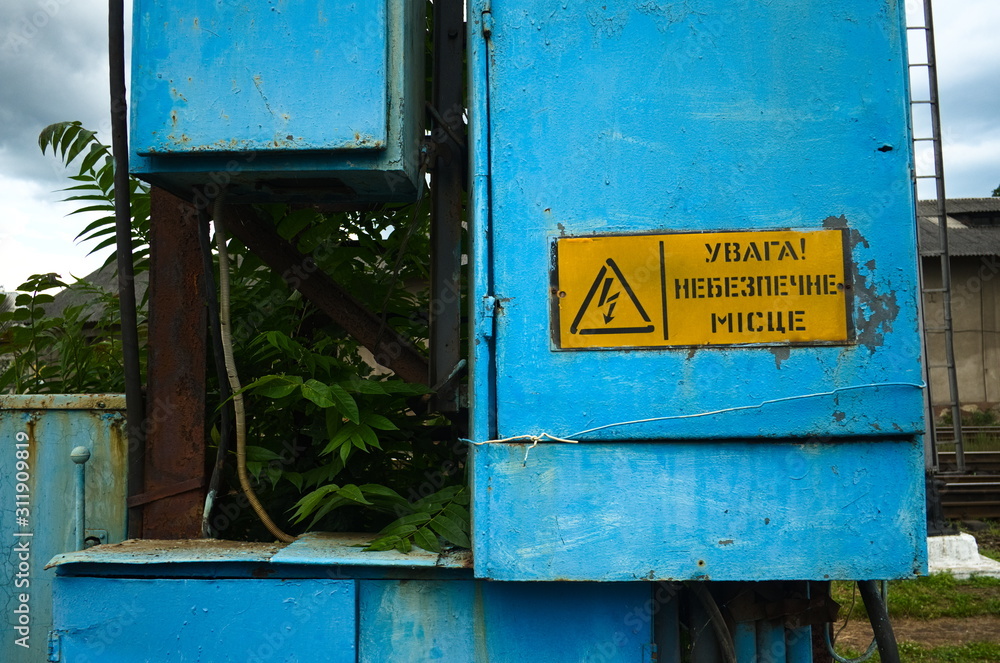 Old high voltage transformer sign on blue metal board. Electric power ...
