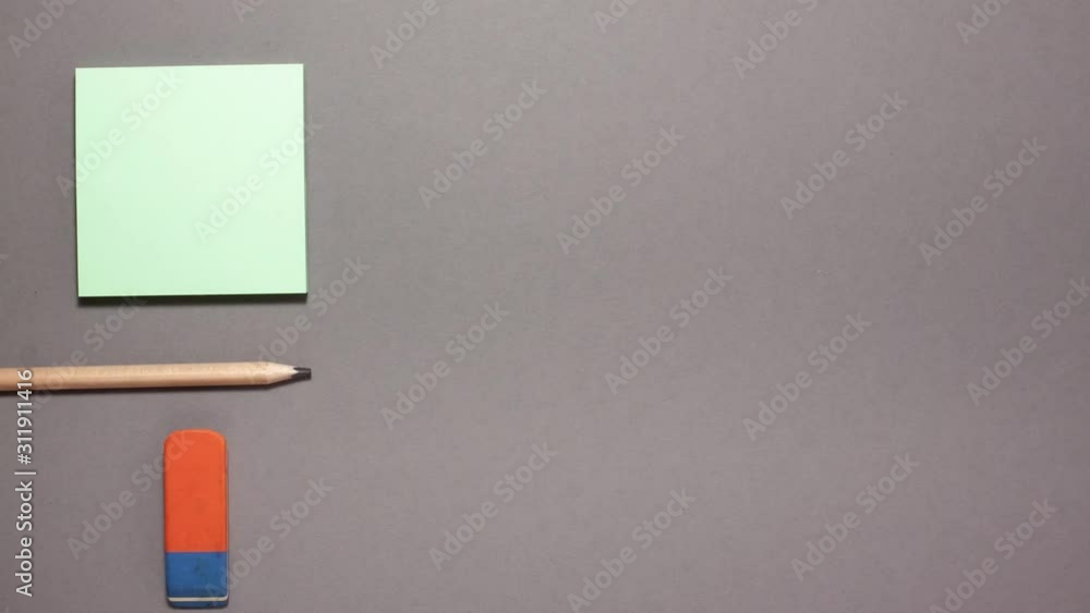 Wooden pen,, sticky note and eraster on gray background. Stop motion ...