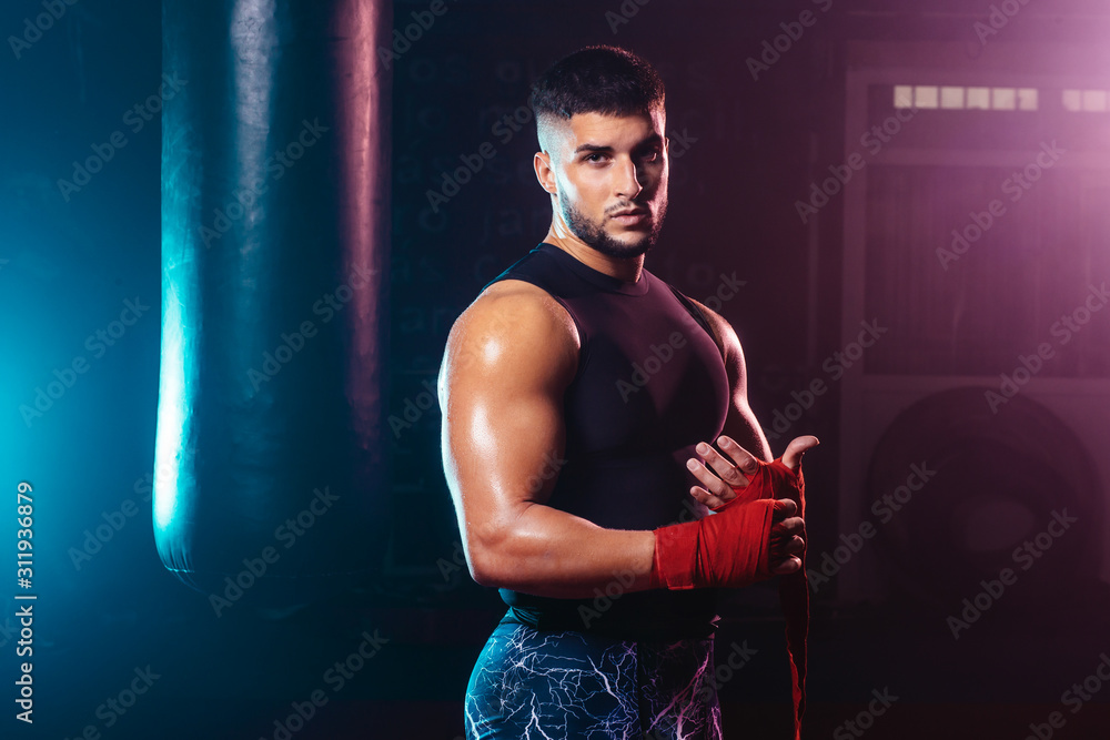 young and muscular man wrapping his hands with boxing hands tape ...