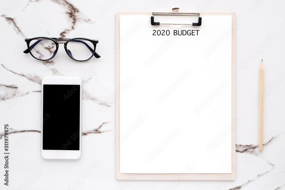 2020 budget on blank note paper and smartphone with blank on screen ...