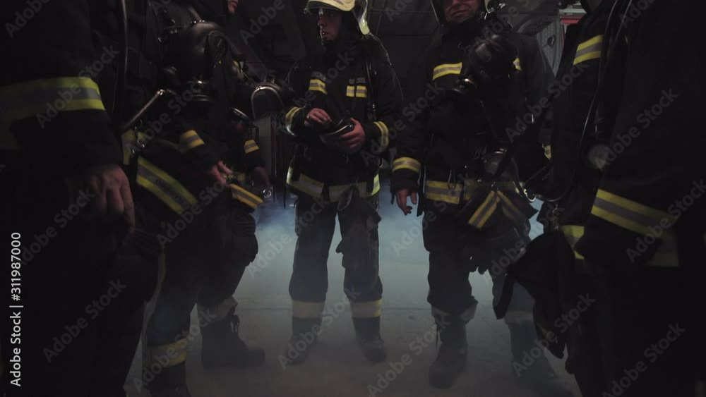 group of five firefighters wearing full equipment. relaxed chatting ...