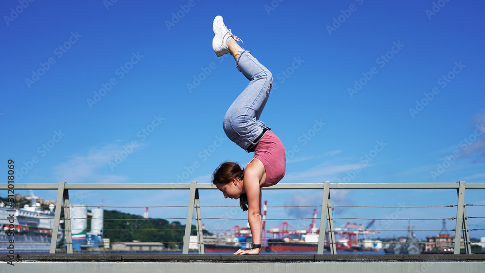 Young flexible girl in life style clothes makes a handstand on ...