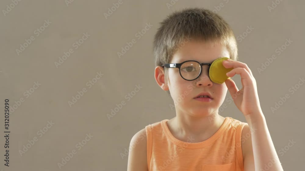 Portrait of funny child in new glasses with yellow spot to correct ...