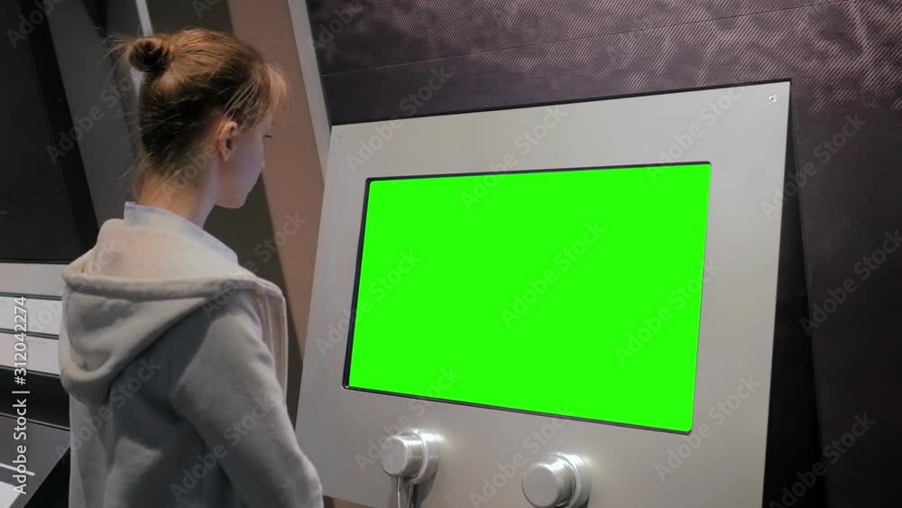 Woman looking at blank digital interactive green display kiosk at ...