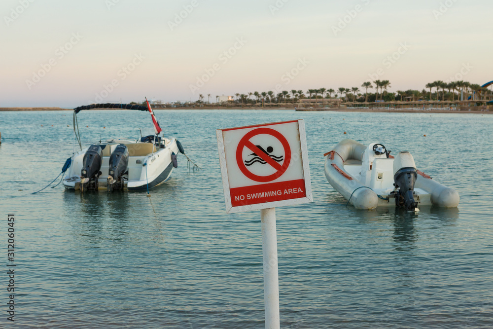 No swimming area sign on the sea beach. Crossed out floating person ...