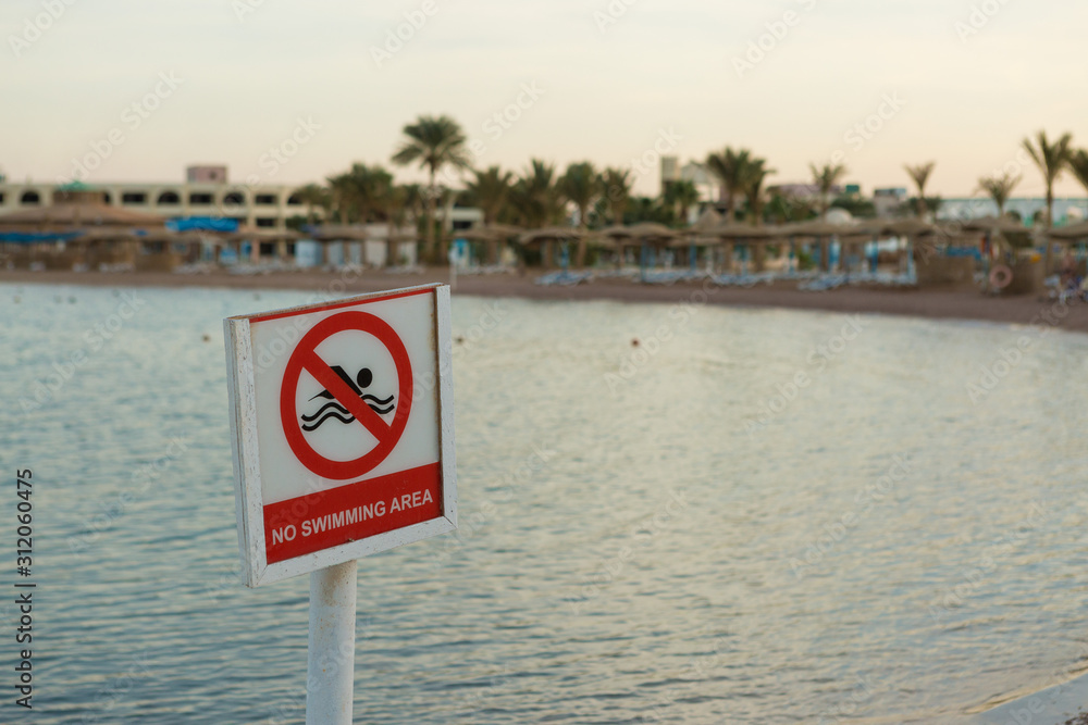 No swimming area sign on the sea beach. Crossed out floating person ...