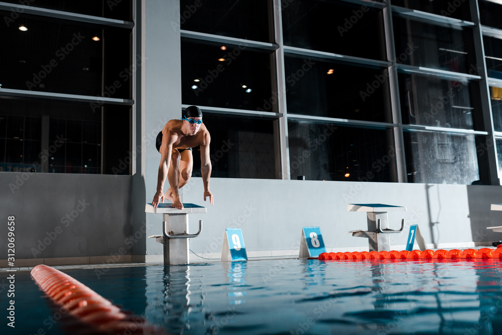 handsome and shirtless swimmer standing in starting pose on diving ...