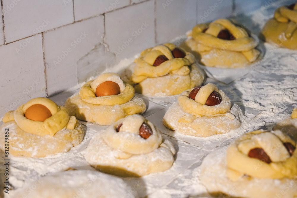 Batch of unbaked traditionally made Easter cakes, also called Folar or ...